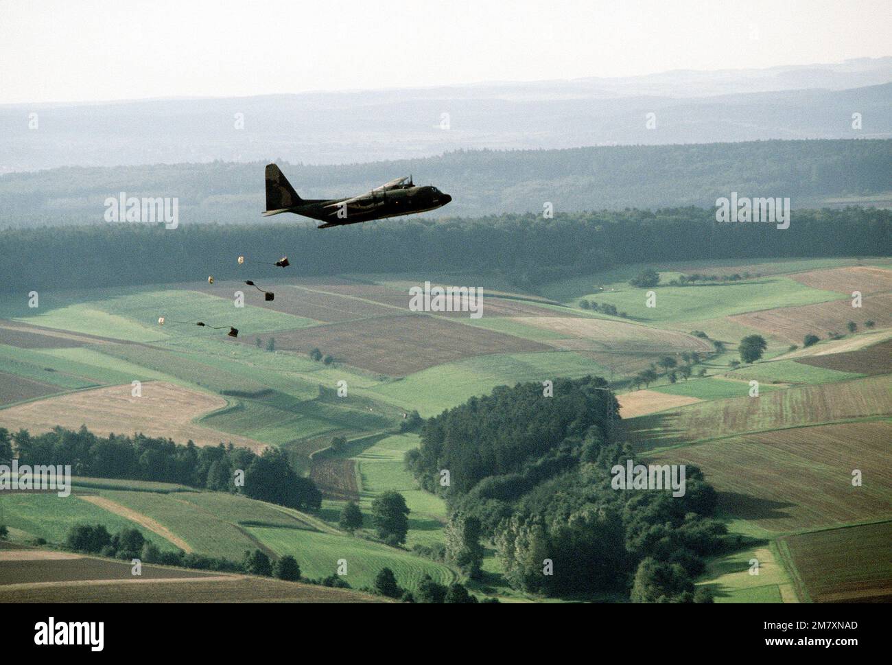A C-130 Hercules aircraft releases three pallets containing c-rations ...