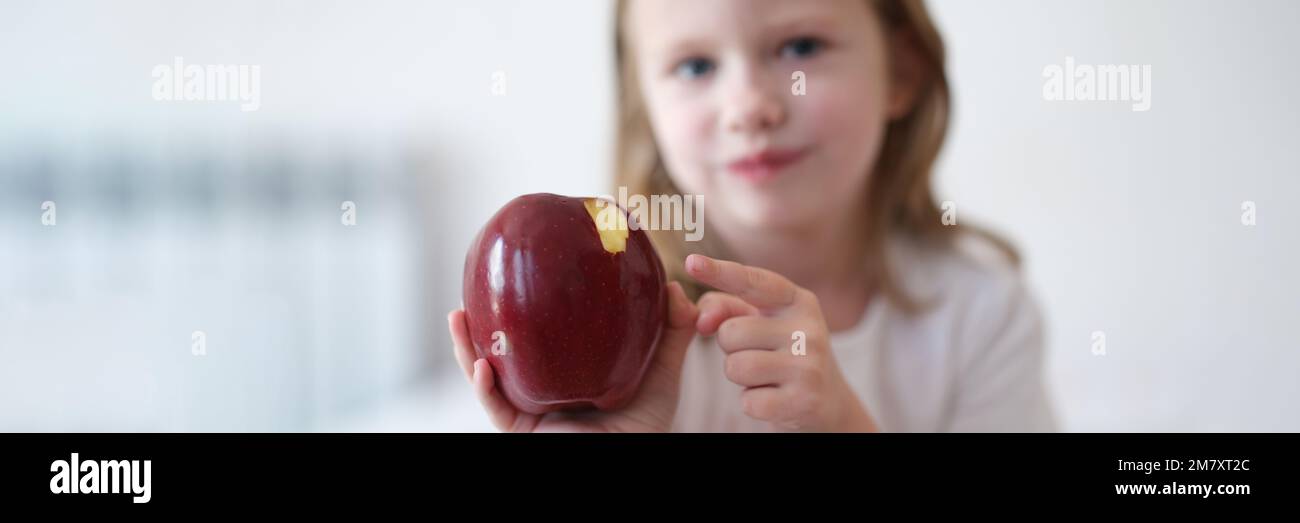 Girl child bites and eats big red apple Stock Photo - Alamy