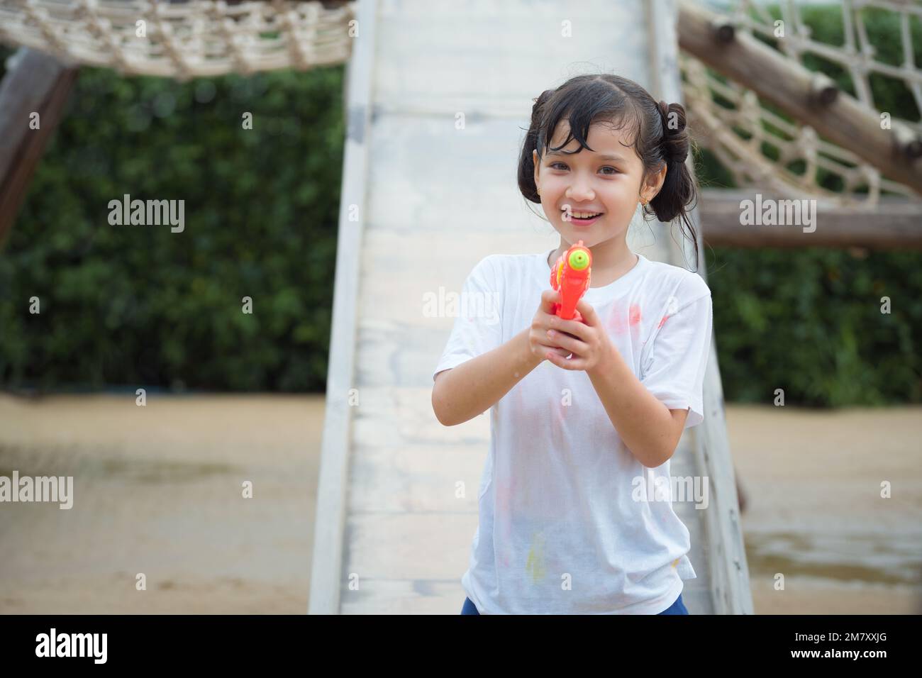 Happy child girl has fun playing sliding and shooting water gun on ...