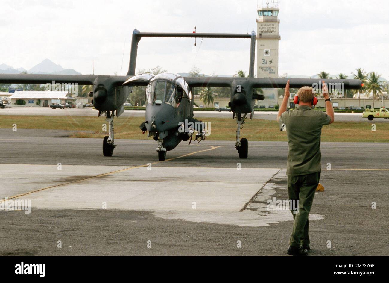 A member of the flight line crew signals taxiing directions to the ...
