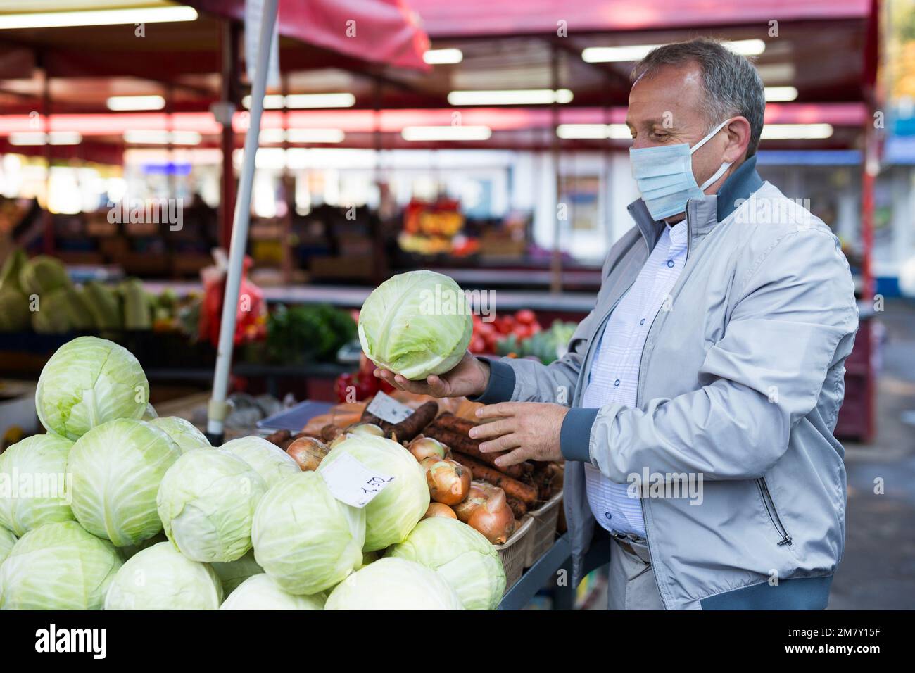 Man in face mask choosing cabbage in market Stock Photo - Alamy