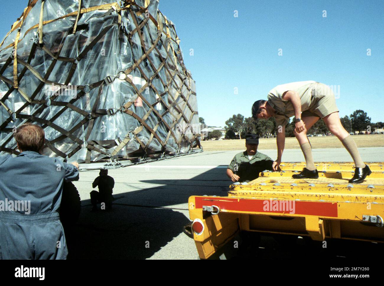 Royal Australian Air Force members help unload a pallet of cargo from a ...