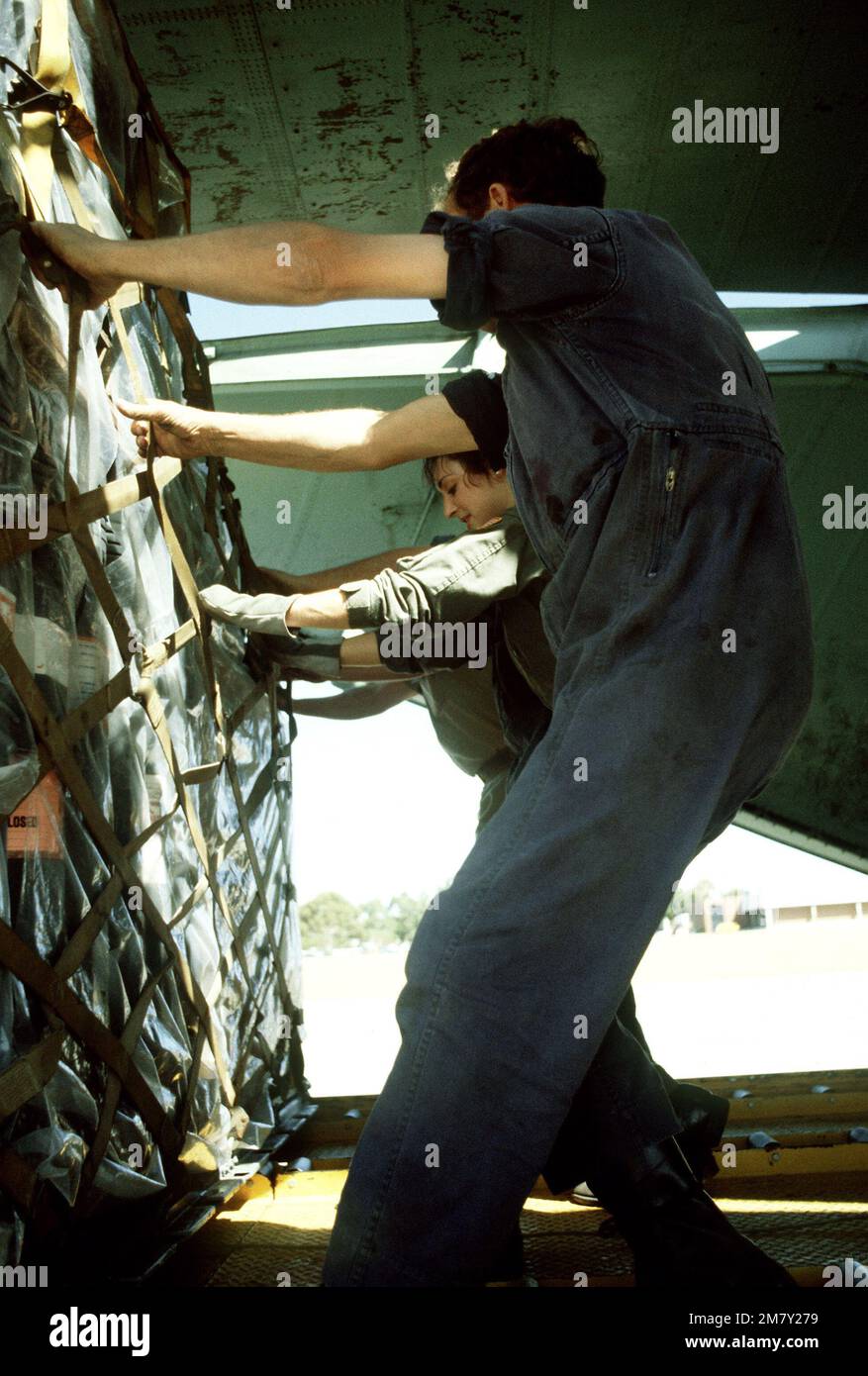 Royal Australian Air Force members help unload a pallet of cargo from a ...