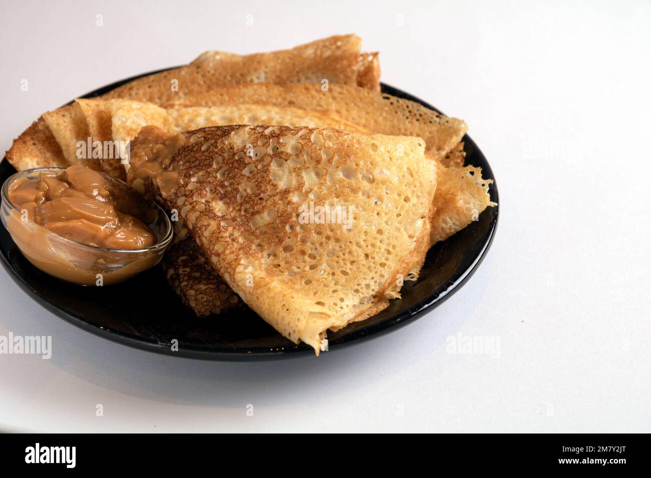 photo triangular-shaped fried pancakes with condensed milk on a white ...