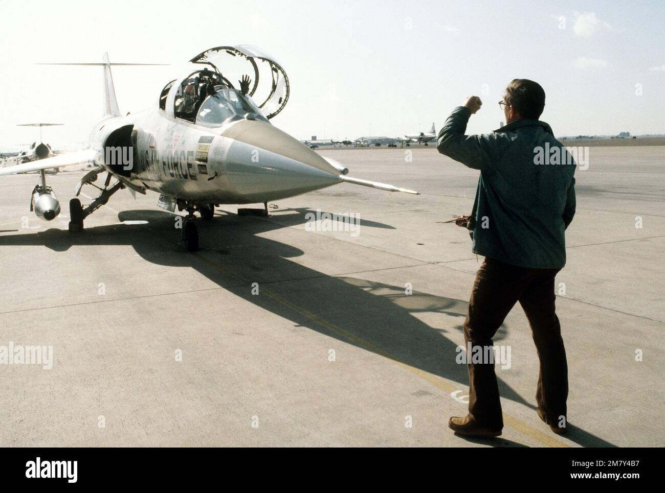 A crew chief directs an F-104G Starfighter aircraft onto the runway ...