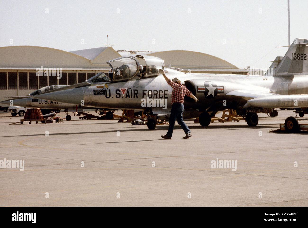 A crew chief directs an F-104G Starfighter aircraft off the flight line ...