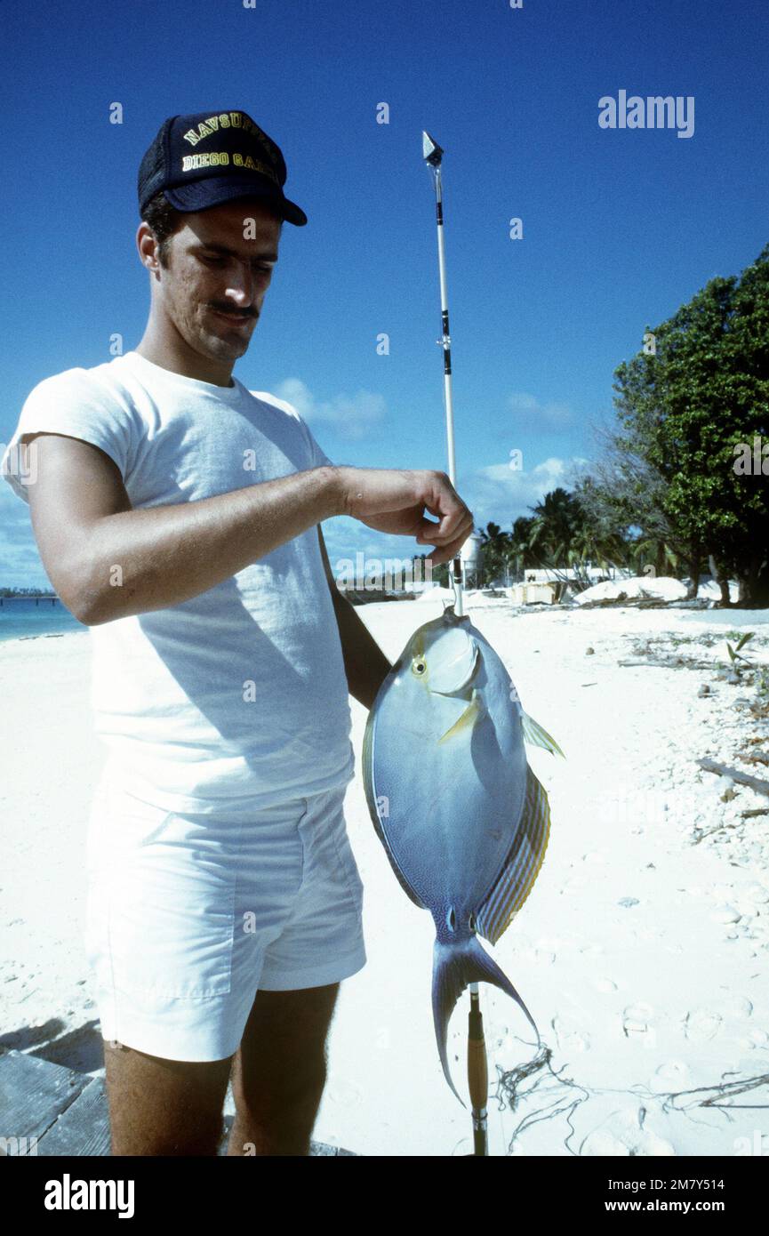 A sailor displays a fish he just caught in the lagoon during his off ...