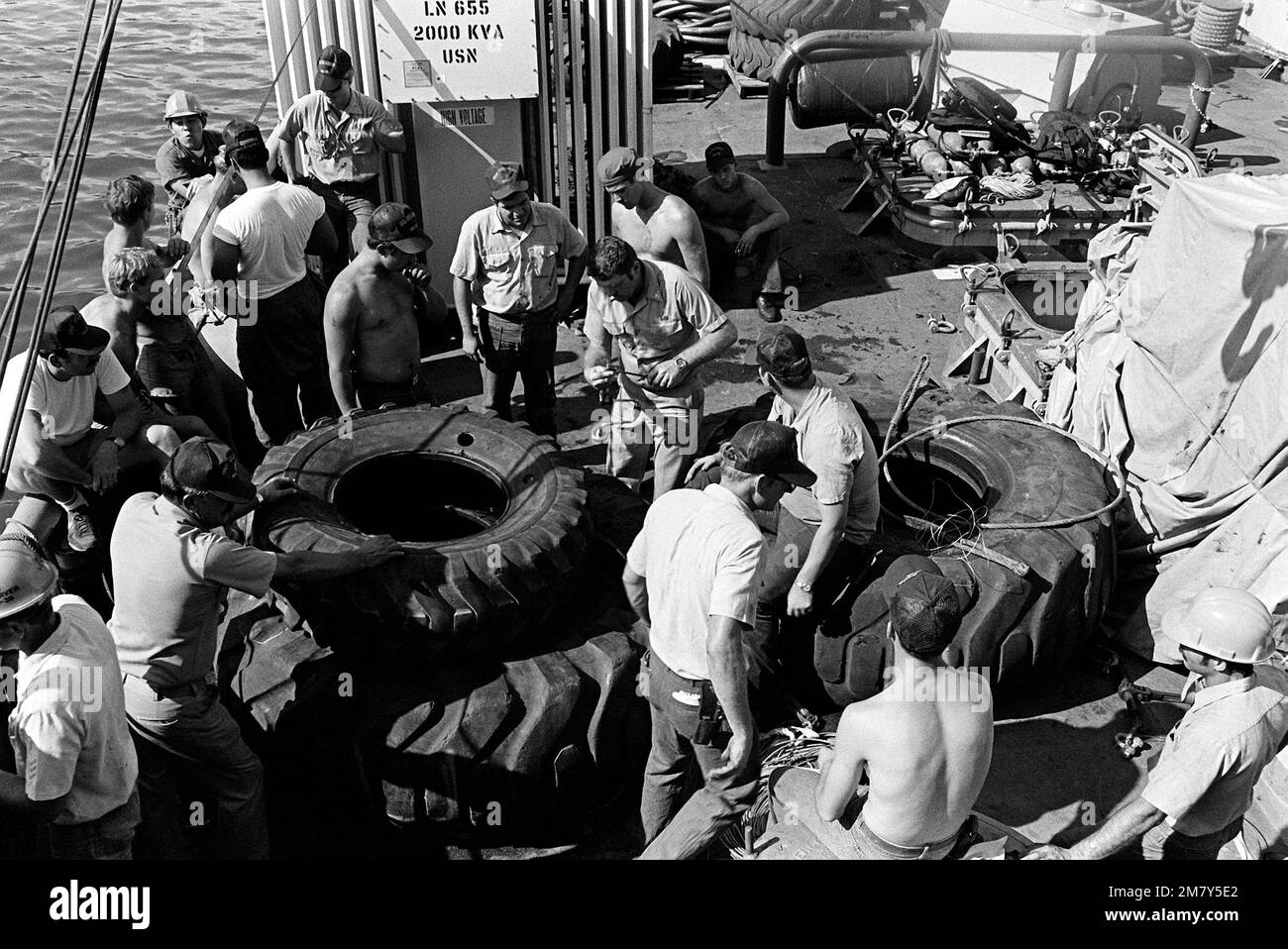 Crewmen aboard the salvage ship USS CONSERVER (ARS-39) attach lines to ...