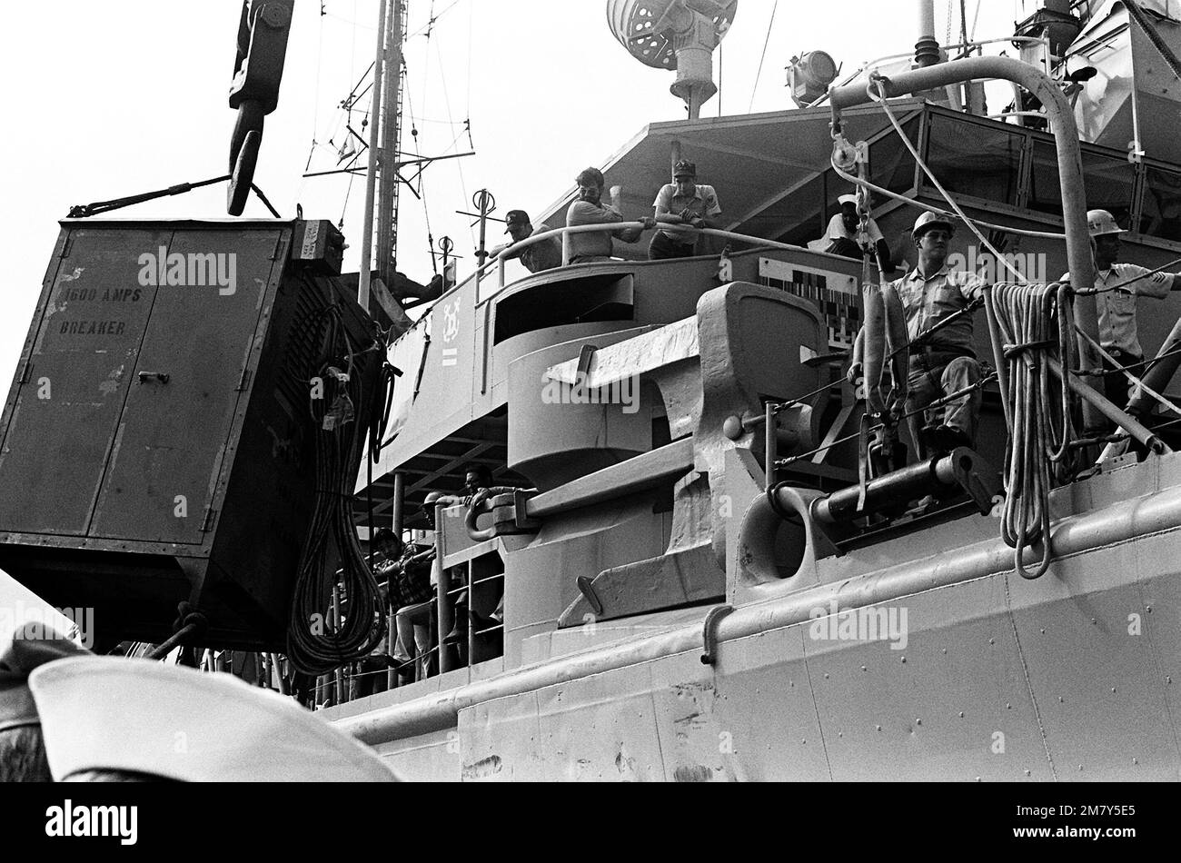 Crewmen aboard the salvage ship USS CONSERVER (ARS-39) prepare to lower ...
