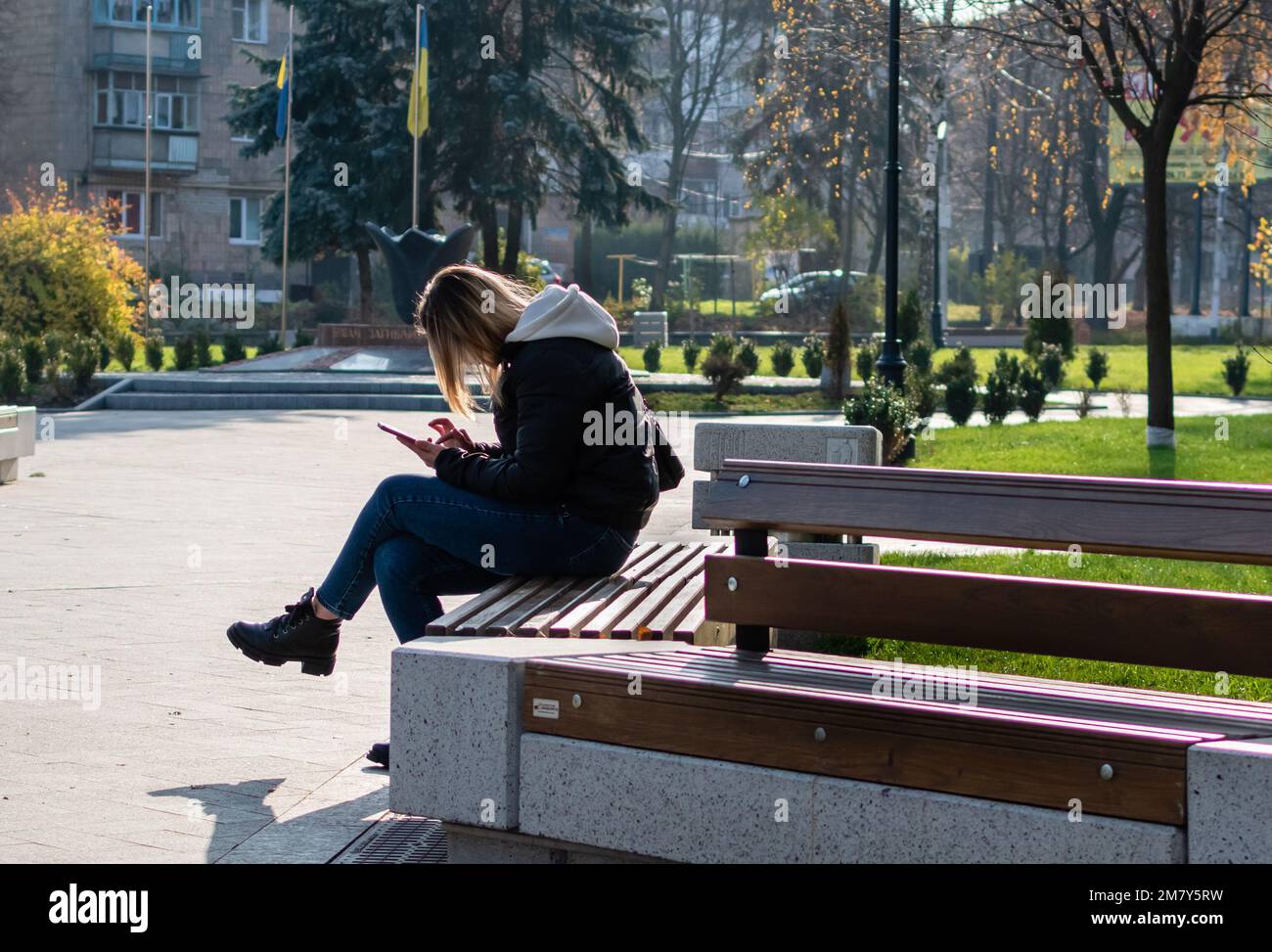 Cute girl sitting on a bench in pedestrian zone and touching her ...