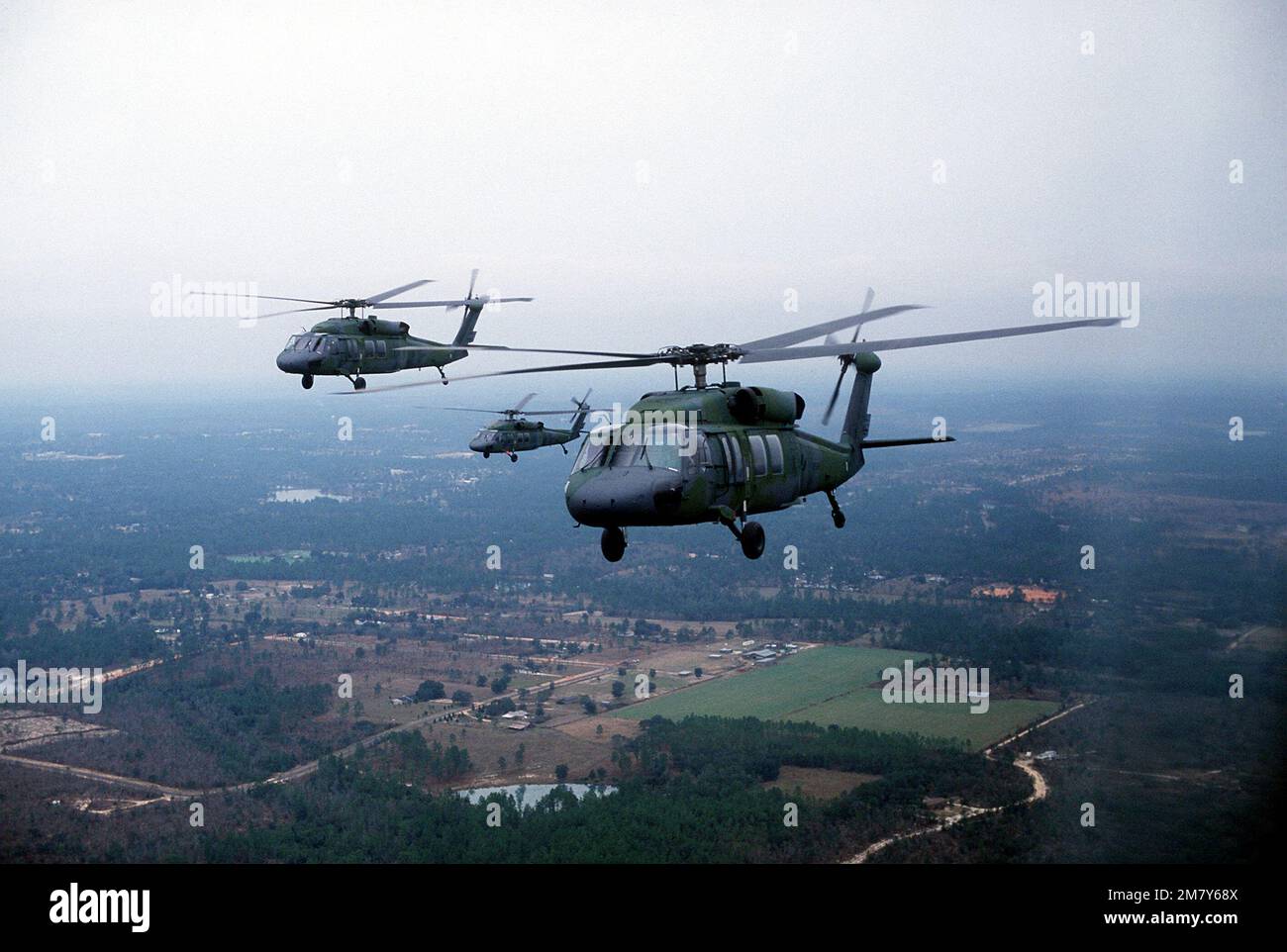An air-to-air left side view of three UH-60A Black Hawk helicopters en ...