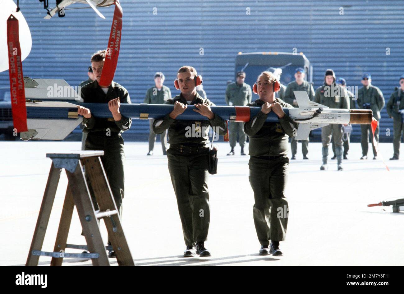 A loading crew carries an AIM-9P Sidewinder missile to be mounted on ...