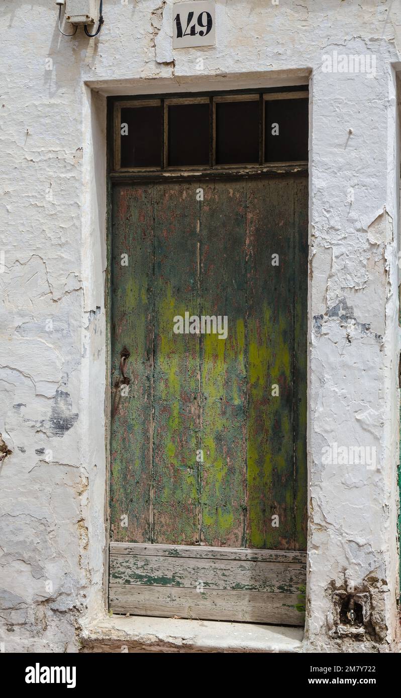 An old distressed green painted door in a white wall on the Spanish ...
