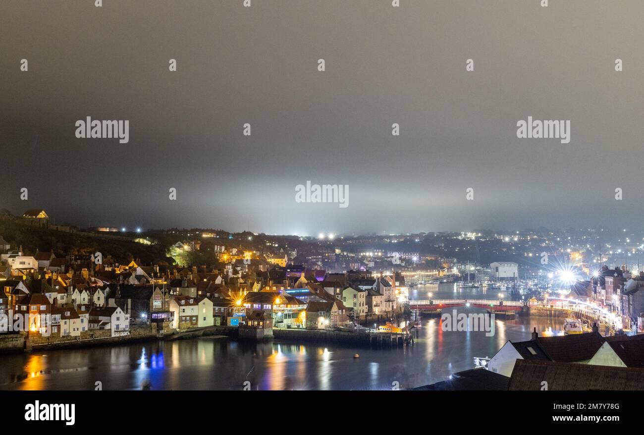 An aerial view of illuminated Whitby harbor on a foggy evening in ...