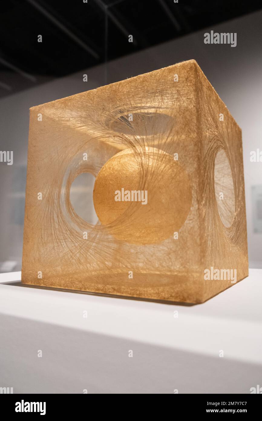 A vertical shot of an art-object of a cube with a ball in it at the ...
