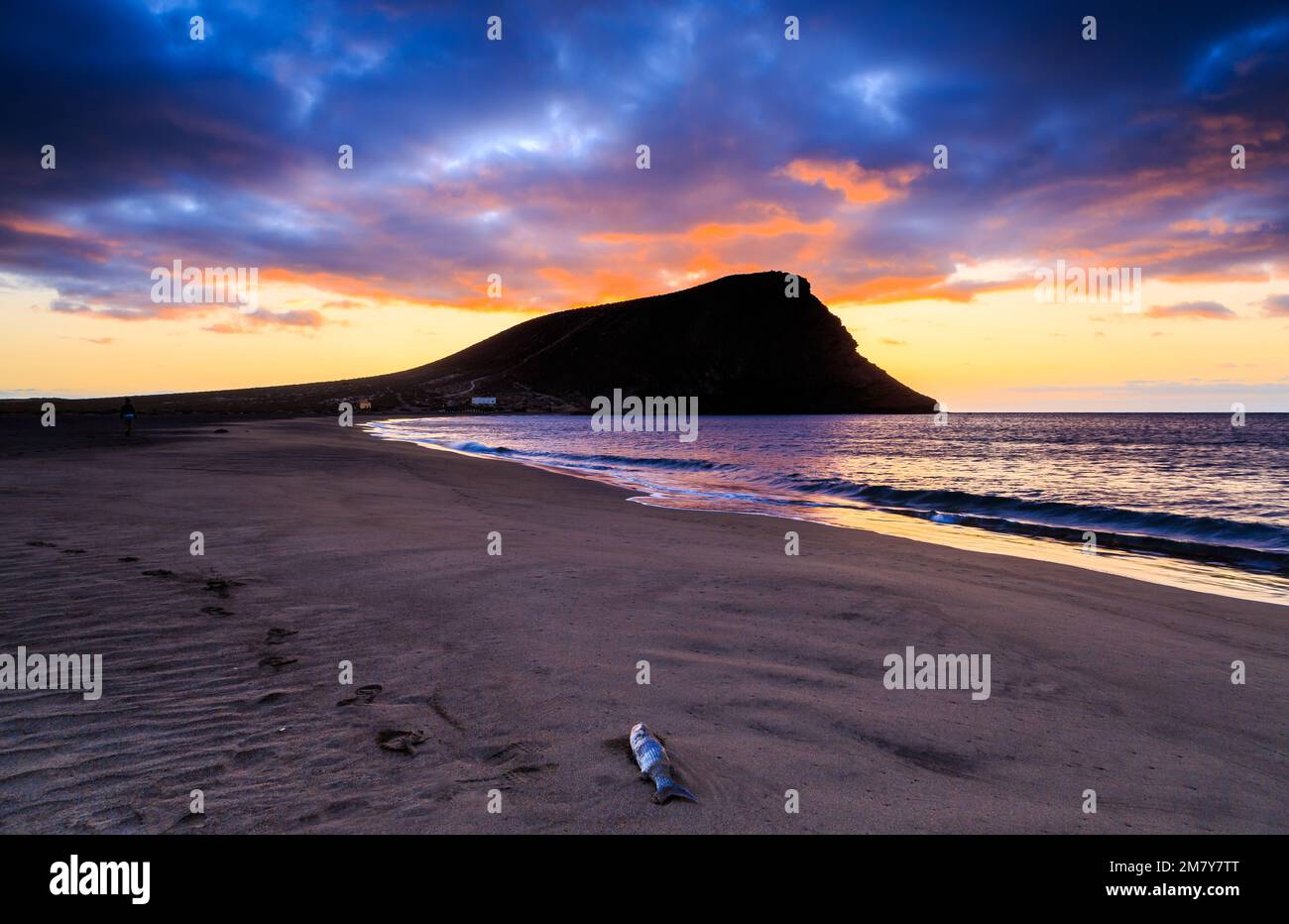 A beautiful shot of a bright sunset sky over a seashore with a cliff on ...