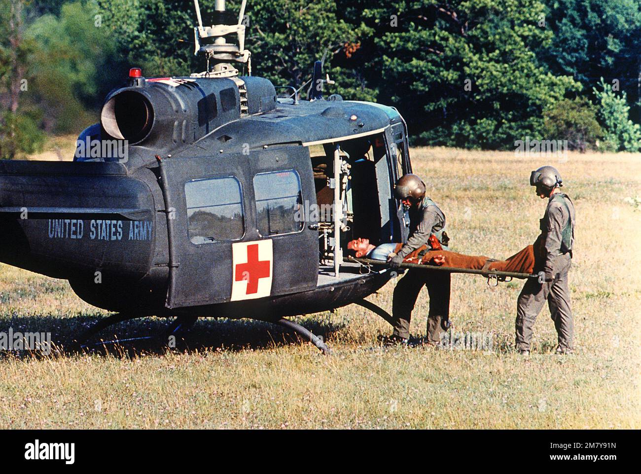 A medical evacuation (MEDEVAC) flight crew loads a patient on a ...