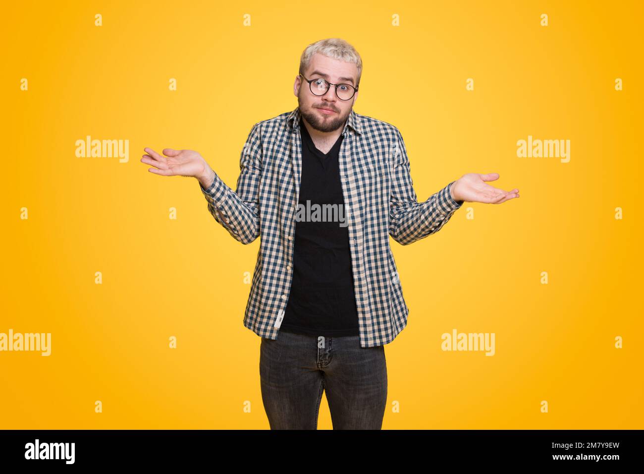 Portrait of young confused man standing and shrugging shoulders ...