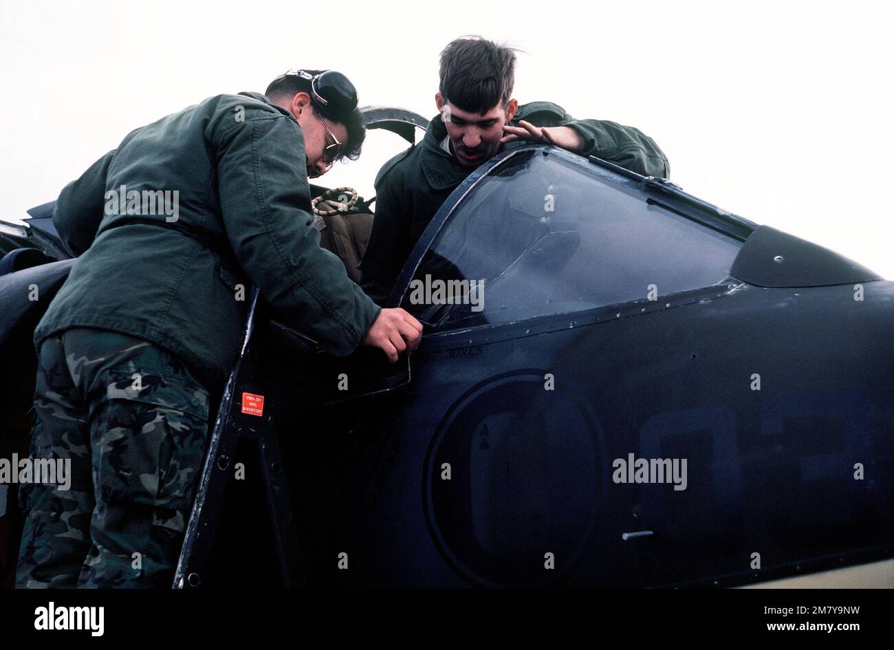A ground crewman assists the pilot of an AV-8B Harrier aircraft from ...