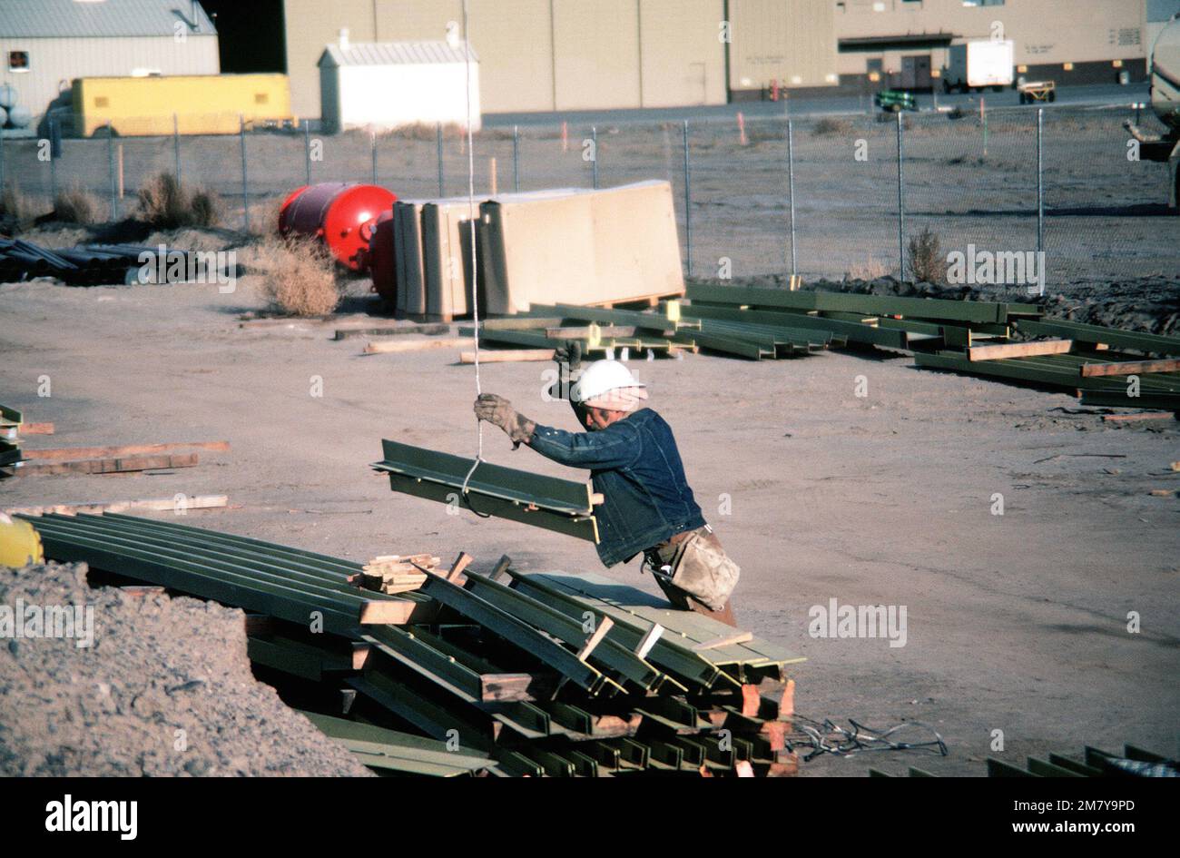 A construction worker attaches a steel beam to a crane during the ...