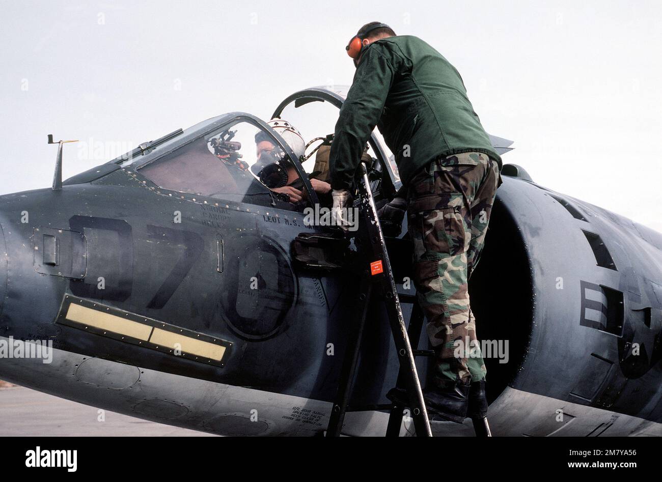 A ground crewman assists the pilot of an AV-8B Harrier aircraft from ...