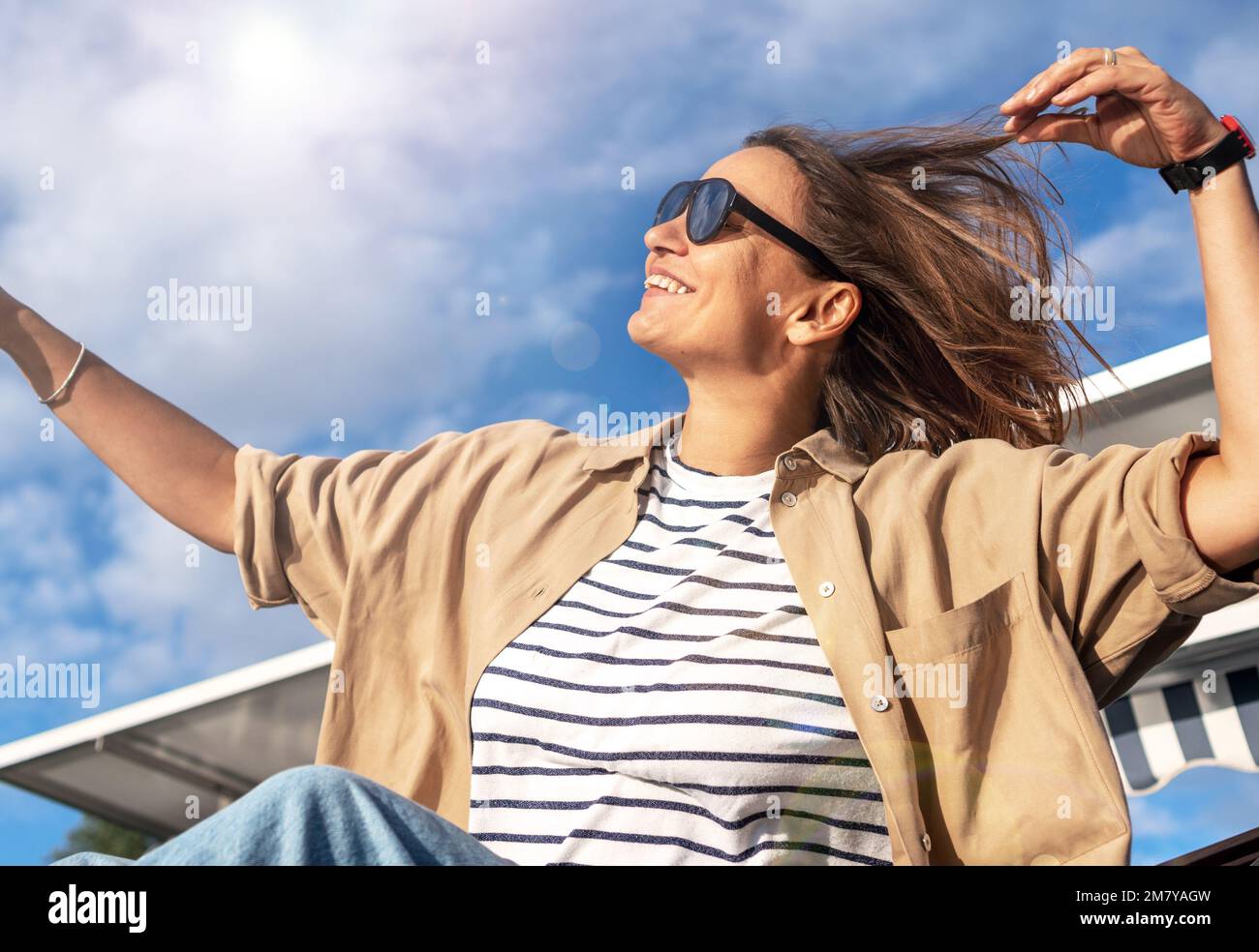 Playful adult woman with sunglasses having fun outdoors enjoying sunny ...