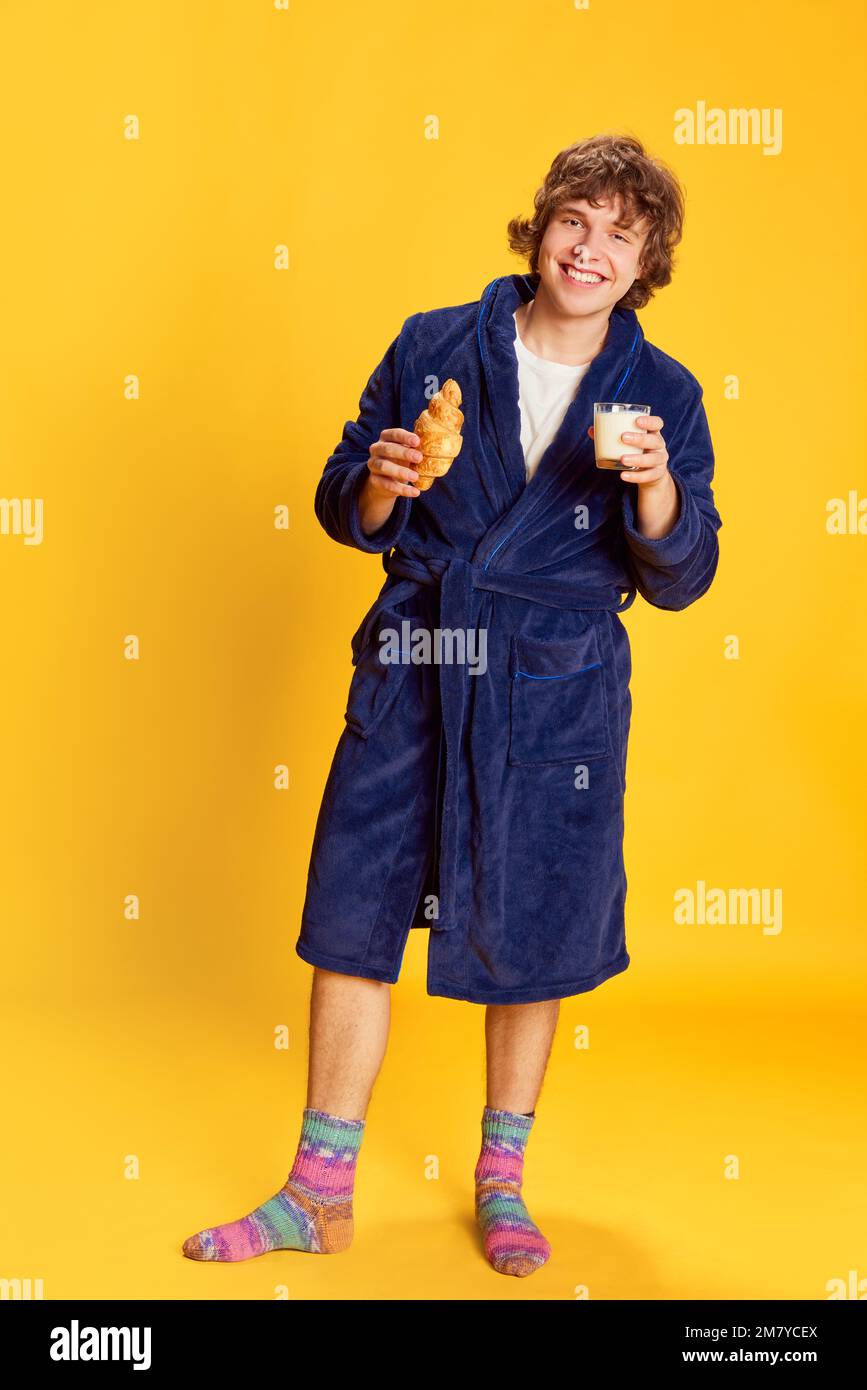 Happiness. Young man wearing bathrobe and having breakfast isolated ...