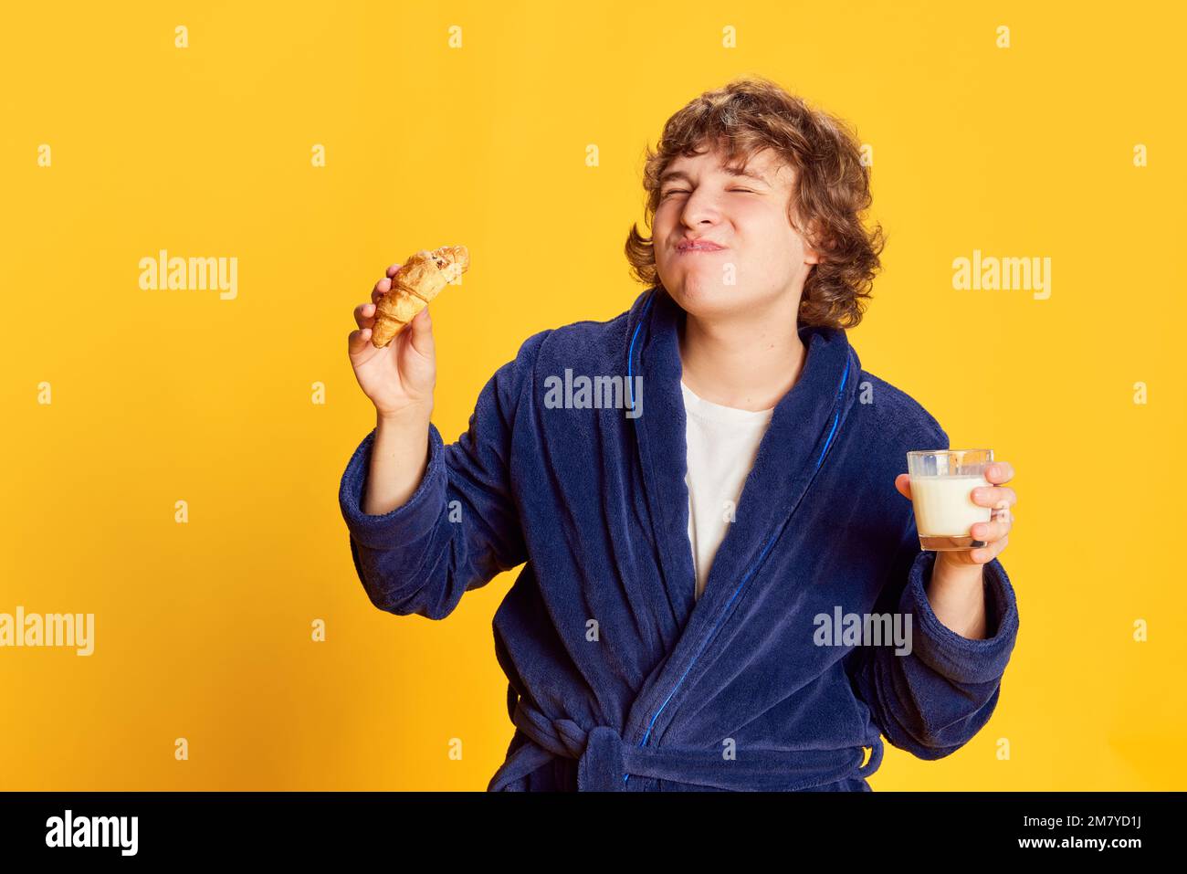 Happiness. Young man wearing bathrobe and having breakfast isolated ...