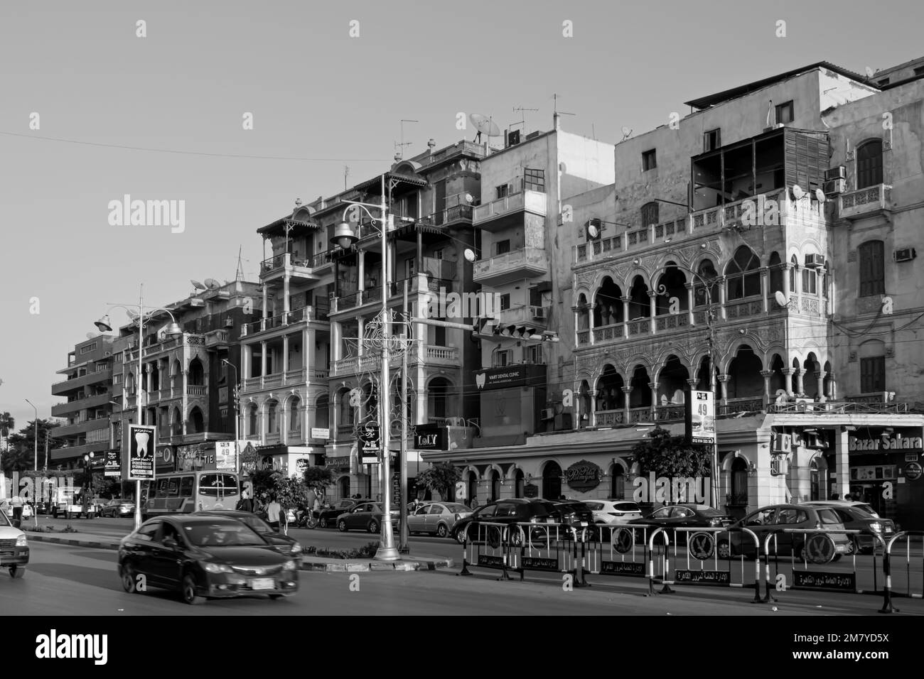 A grayscale of old historical buildings and cars driving down the ...