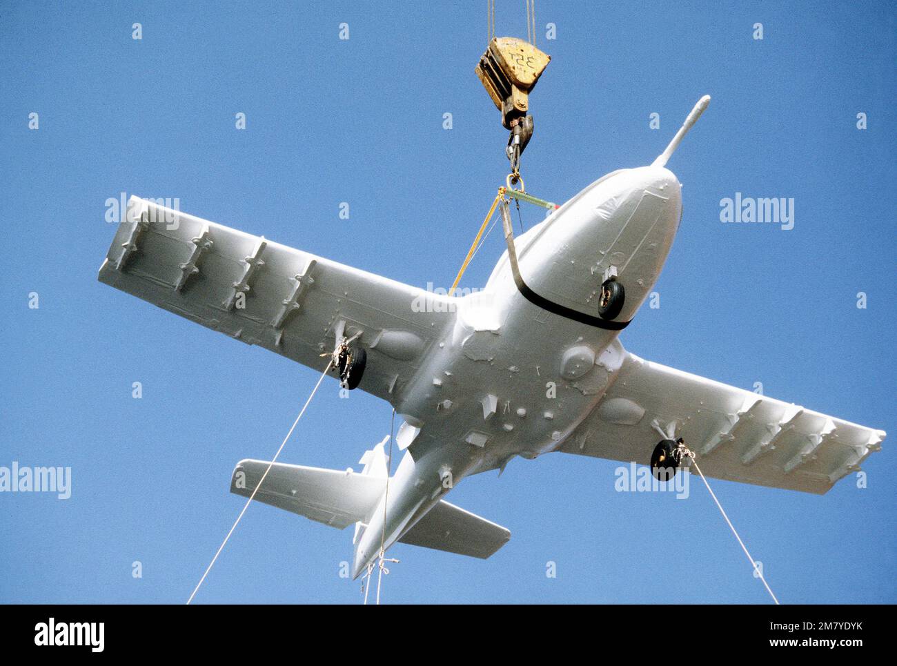 A floating crane lowers an A-37 Dragonfly aircraft from the container ...