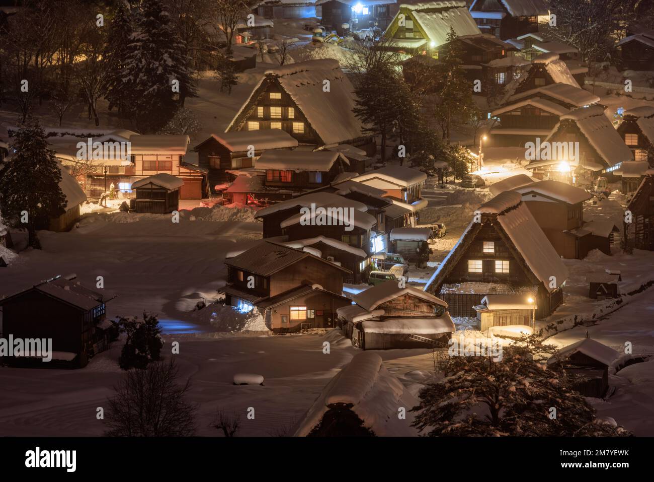 Colorful lights from small mountain village in snowy winter landscape ...