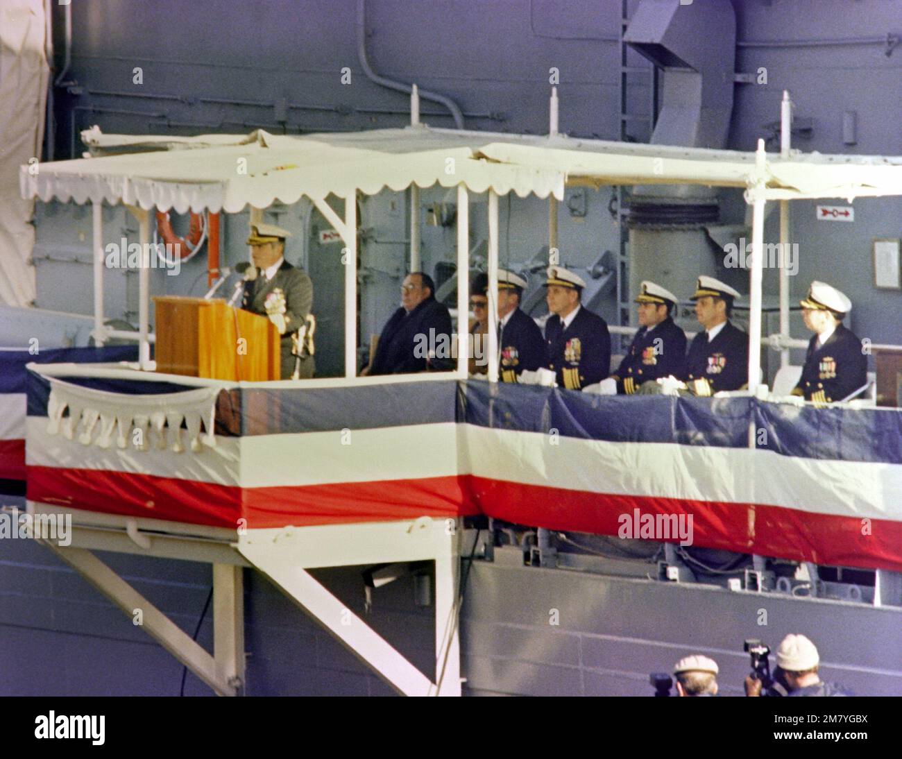 A naval officer addresses guests during the commissioning of the guided ...