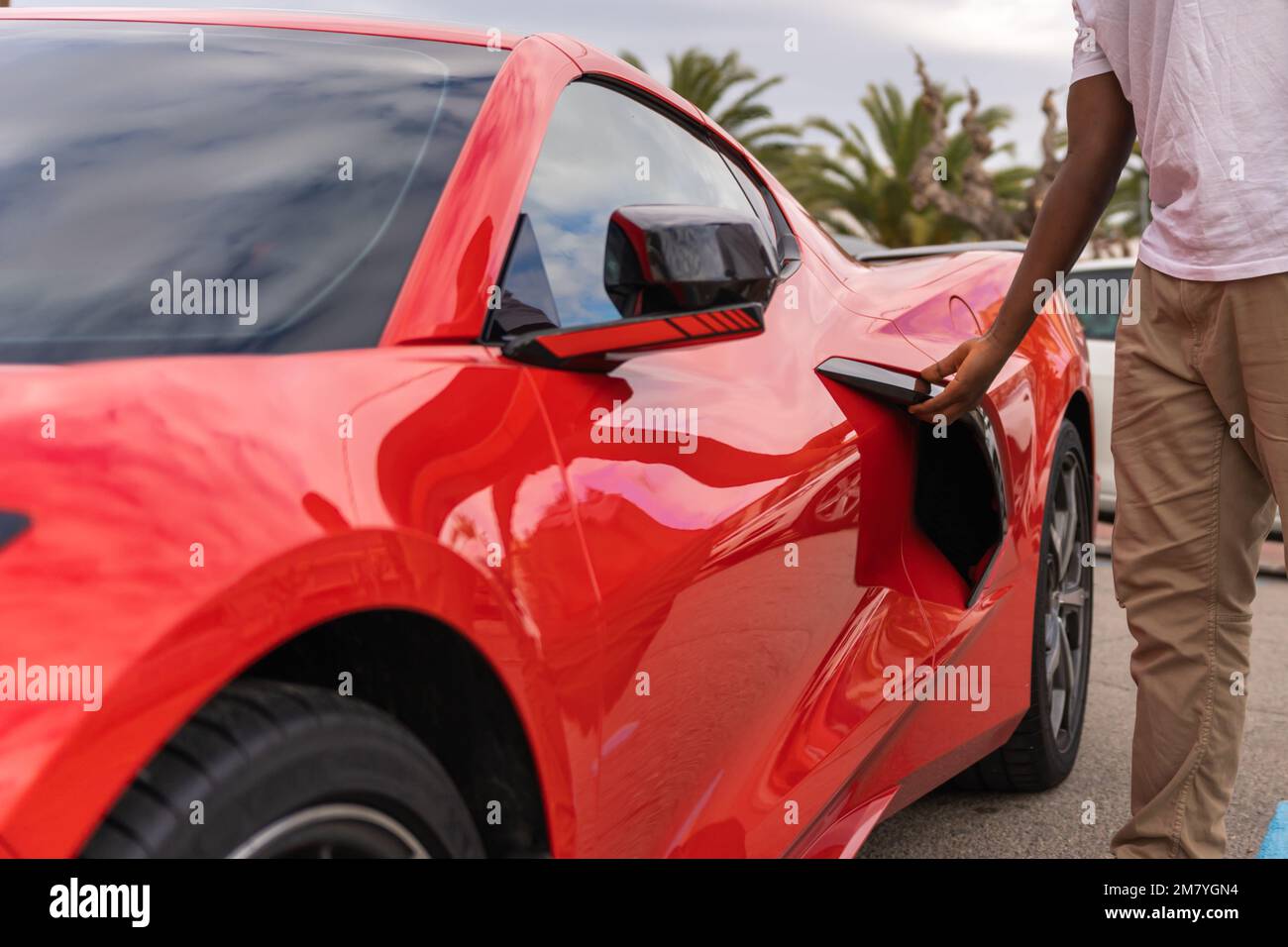 Crop anonymous male traveler in casual clothes standing near modern red ...