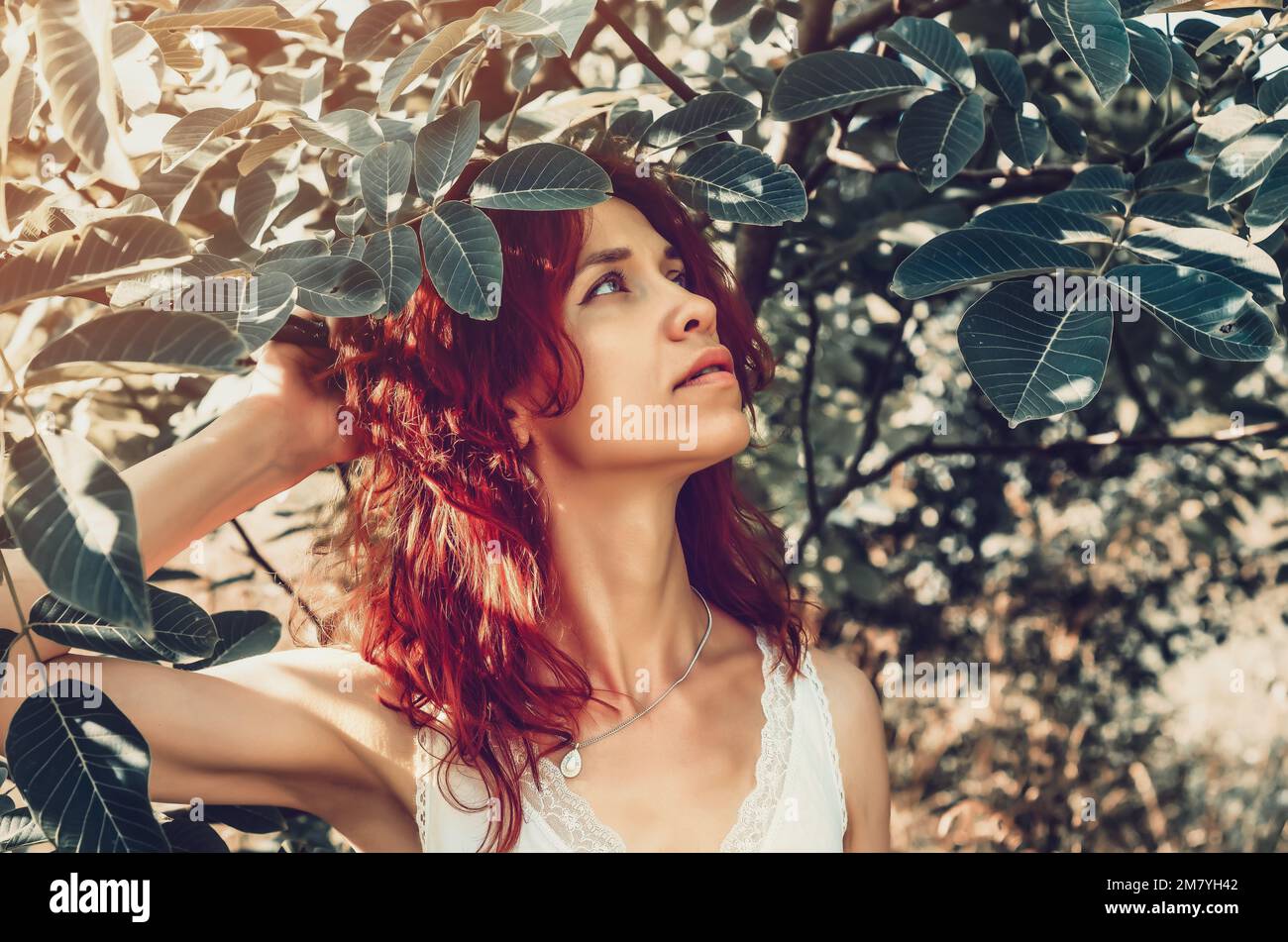 Portrait of a red-haired young girl among the trees in the garden Stock ...