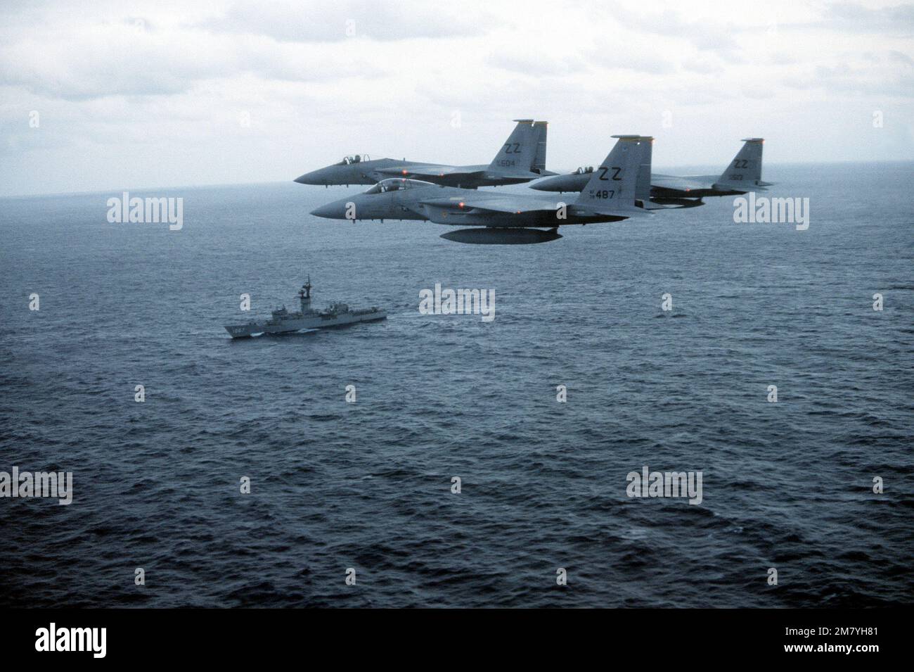 An air-to-air left side view of three F-15 Eagle aircraft flying over ...