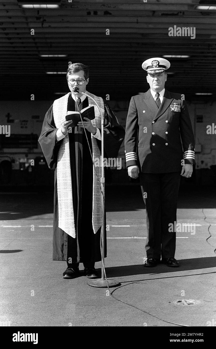 The ship's chaplain and commanding officer participate in a burial at ...