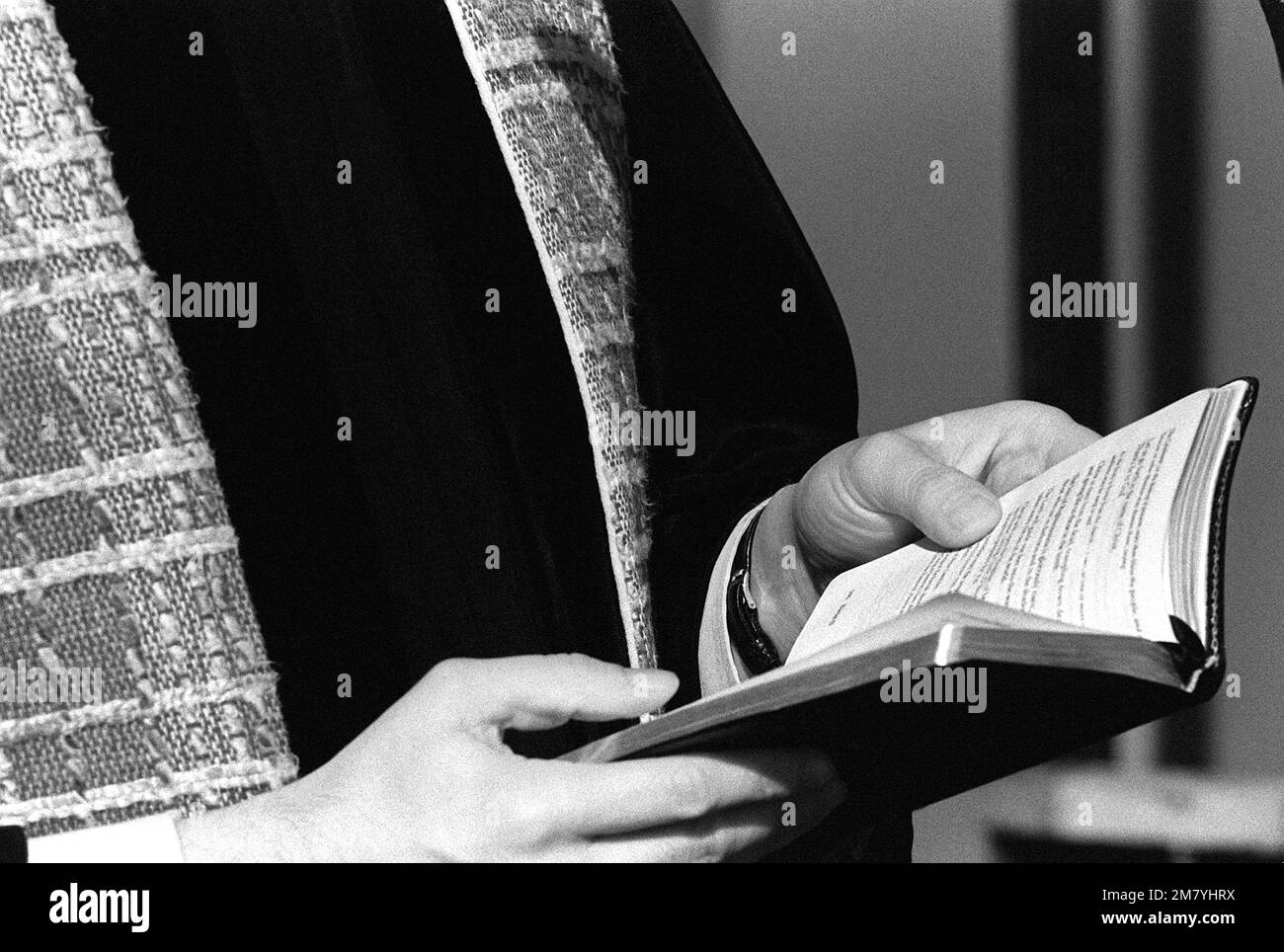 A close-up of the ship's chaplain holding an open Bible during a burial ...