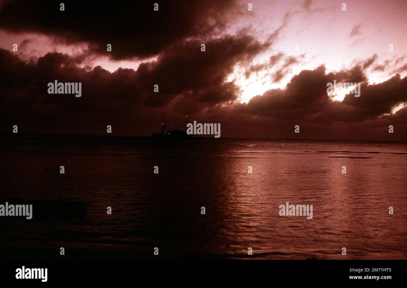 A port beam view of the salvage ship USS BOLSTER (ARS 38) silhouetted ...