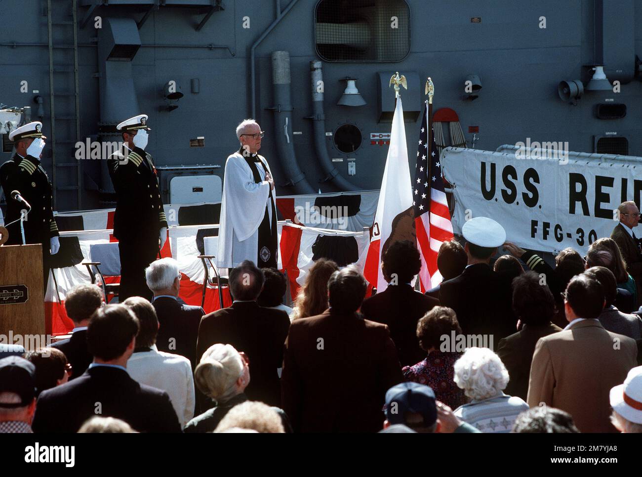 Distinguished guests on the speakers platform stand to view the color ...