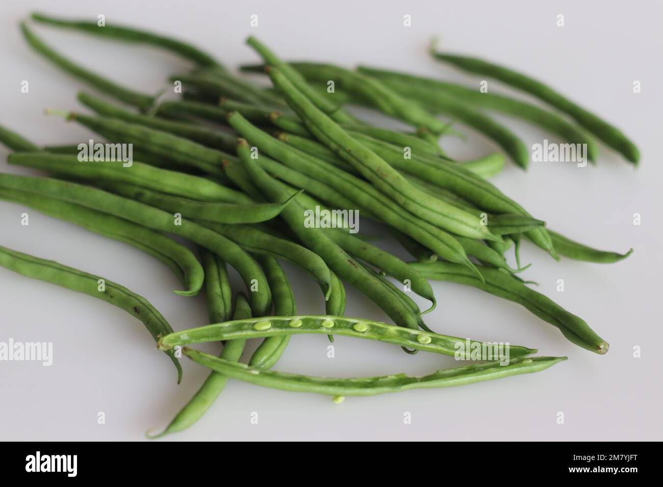 Bunch of French Beans shot on white back ground with few sliced half ...