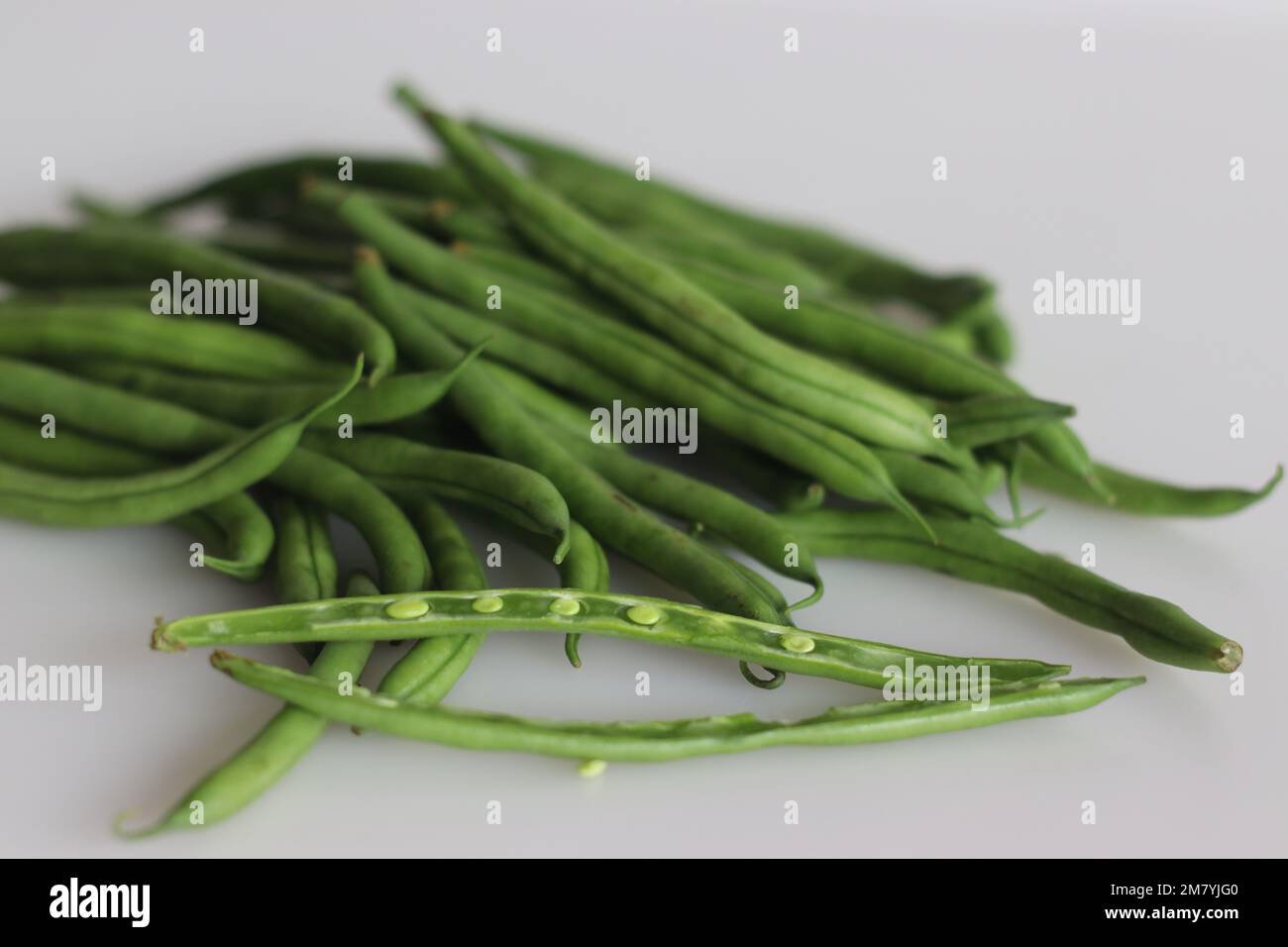 Bunch of French Beans shot on white back ground with few sliced half ...