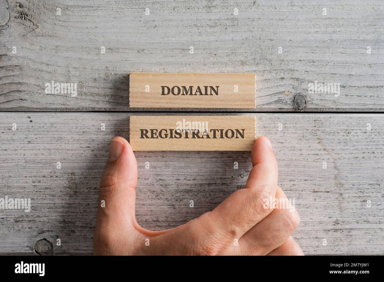 Male hand stacking two wooden blocks with a Domain registration sign on ...