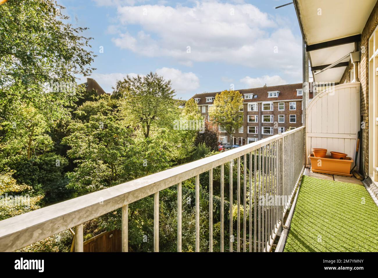 a balcony with green grass and trees in the foreground, taken from an ...