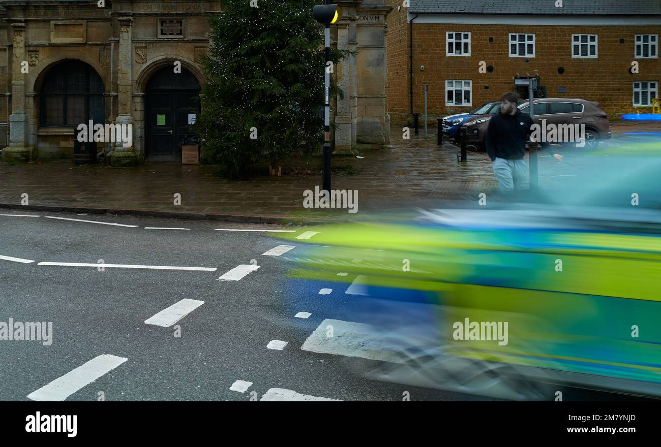 A police car speeds over a pedestrian crosssing and along a street in ...