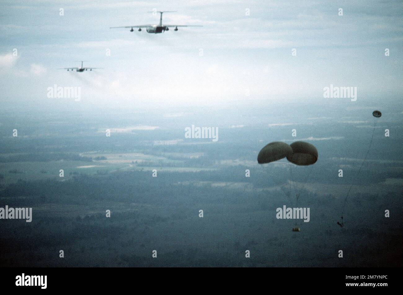 An air-to-air left rear view of two C-141B Starlifter aircraft from the ...