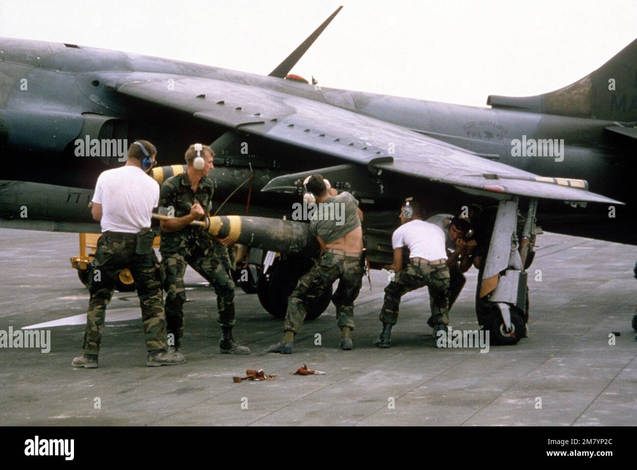 Ordnance loading operations take place on an AV-8B Harrier aircraft ...