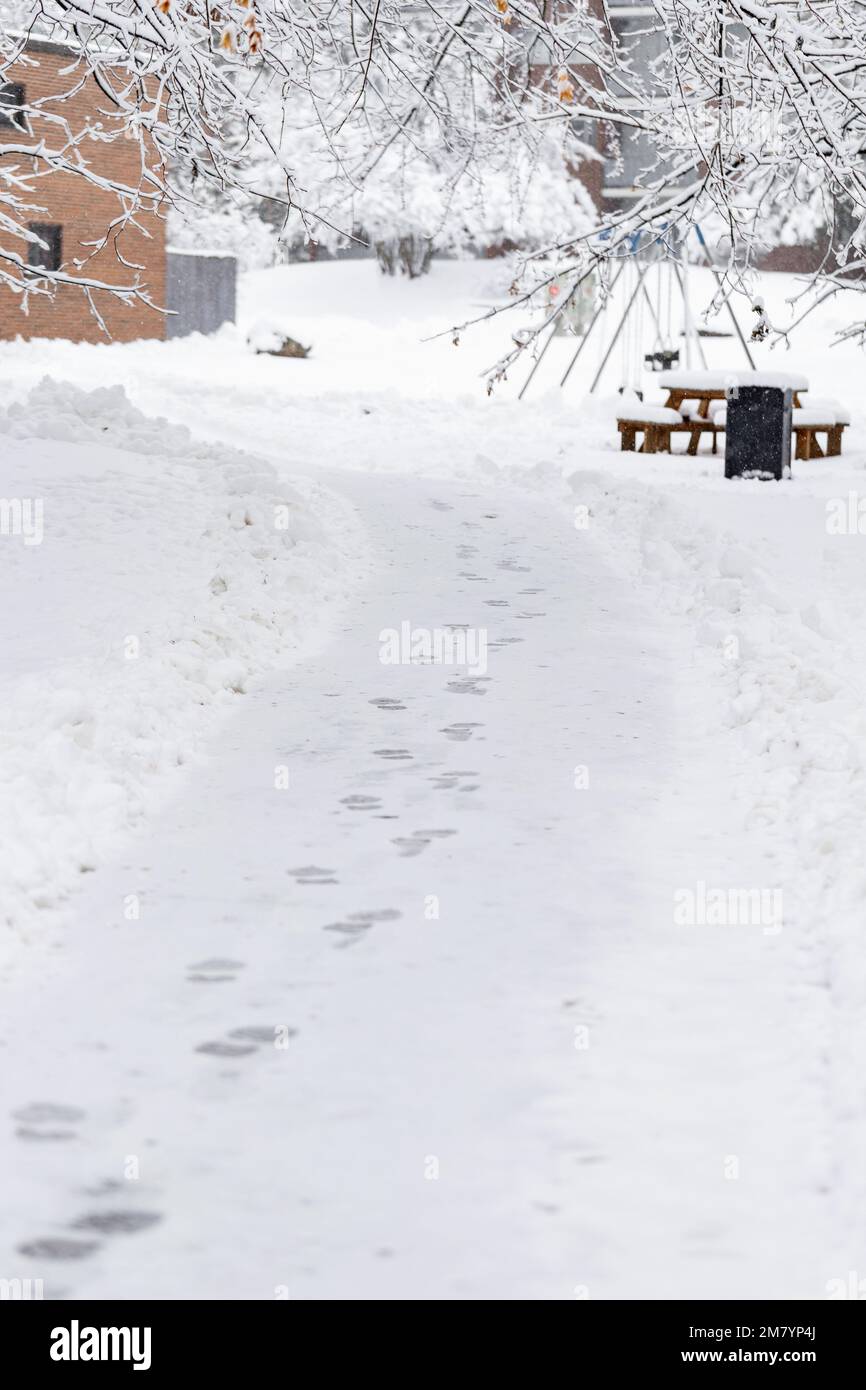 Snow on sidewalk leading to the house and playground in the yard. Snowy ...