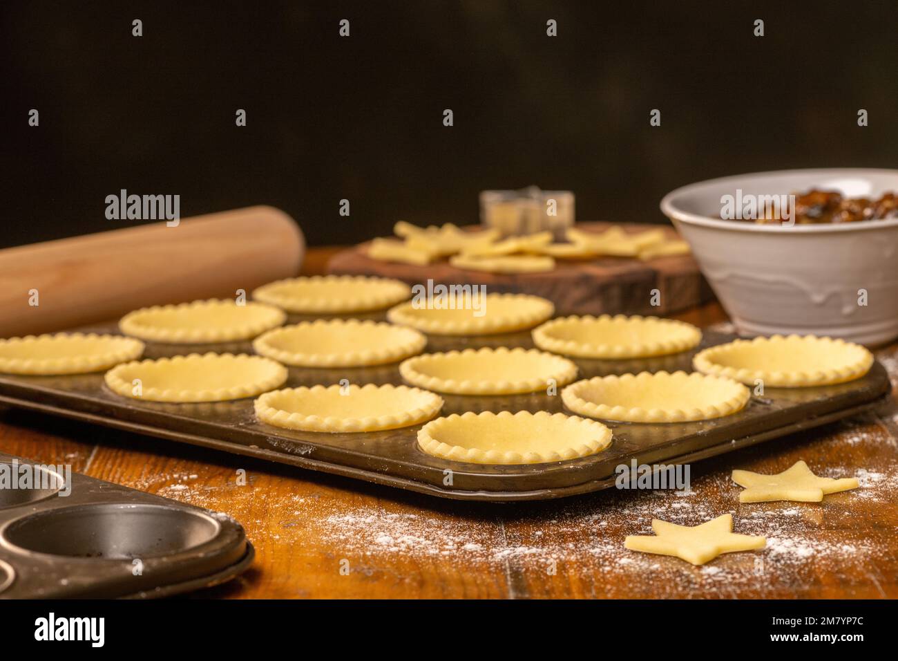 Side view of metal tray of uncooked pastry cases with fluted edges ...