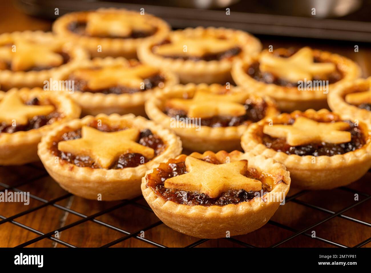 Closeup of mince pies topped with pastry stars cooling on a metal rack ...