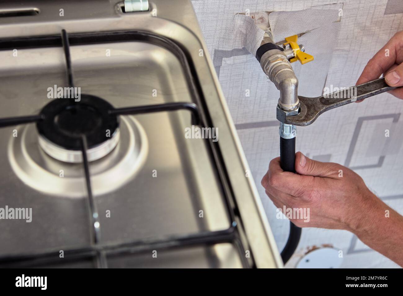 Gasman disconnects flexible hose from gas stove Stock Photo - Alamy